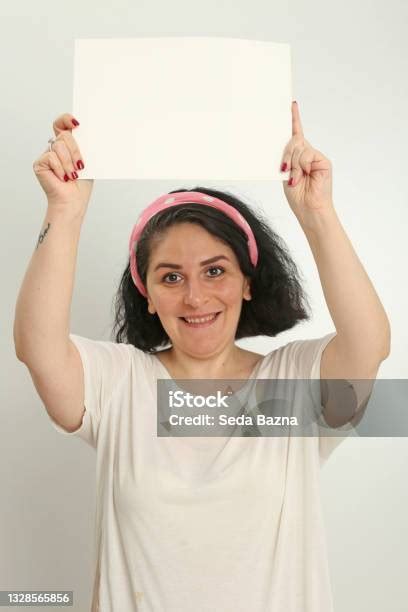 ภาพสตูดิโอของผู้หญิงน่ารักถือป้ายเปล่ากับด้านหน้าของพื้นหลังสีขาว ภาพสต็อก ดาวน์โหลดรูปภาพ
