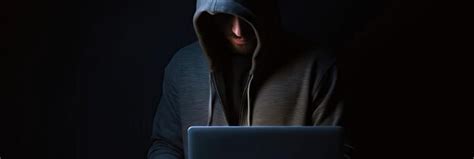 premium ai image hacker without face in a hood holds a laptop on a