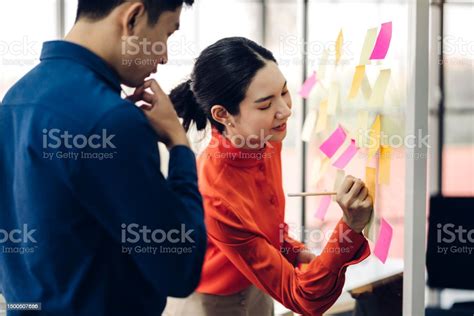 두 명의 캐주얼 비즈니스 사람들이 현대 사무실의 유리 창에 스티커 메모와 함께 프로젝트를 통해 작성하고 브레인 스토밍 팀워크 컨셉 20 24세에 대한 스톡 사진 및 기타