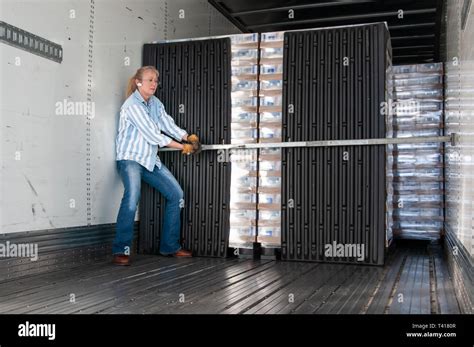 Pretty Blonde Woman Placing A Load Lock In The Inside Of A Trailer To Secure The Loaded Pallets