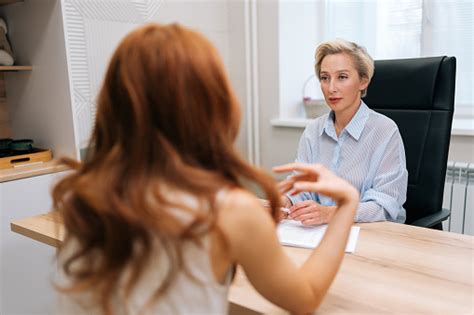정체를 알 수 없는 여성 환자의 어깨에서 숙련된 중년 여성 의사까지 의료 보고서 결과나 재활 소식을 설명하고 도움의 조언을 하는 모습 25 29세에 대한 스톡 사진 및 기타