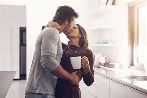Love Intimate And Kiss With A Couple In The Kitchen Of Their Home