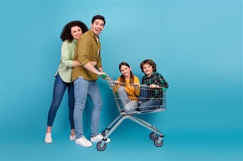 기쁨과 유대감을 보여주는 파란색 배경에 활기찬 쇼핑 카트와 함께 유대감을 형성하는 순간을 즐기는 행복한 가족 10 11세에 대한 스톡 사진 및 기타 이미지 Istock