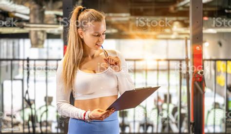 Young Fitness Trainer Making Schedule For A Client On The Clipboard At