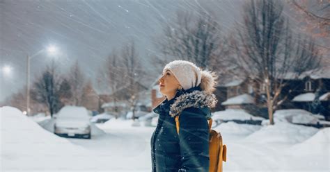 파란색 재킷 겨울 옷과 모자를 쓴 여자가 눈 아래 야외를 걷고 있다 가로등 아래 서서 밤 저녁에 떨어지는 눈을 바라보는 여자 겨울 낭만적 인 원더 랜드 사진