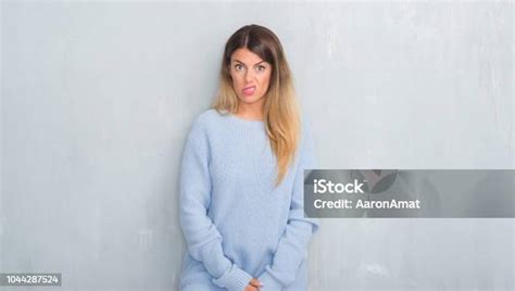 젊은 성인 여자 문제 때문에 겨울 옷 의심과 긴장 찡그림 화가 입고 회색 그런 지 벽에 부정적인 사람입니다 가을에 대한 스톡 사진 및 기타 이미지 Istock