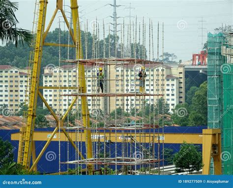 Construction Workers Wearing Safety Gear And Safety Harness While Installing Scaffolding At A