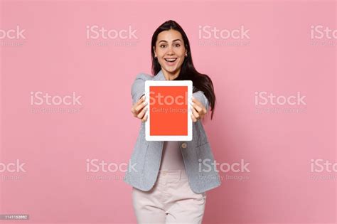 분홍색 파스텔 배경에 고립 된 빈 빈 화면으로 태블릿 Pc 컴퓨터를 들고 줄무늬 재킷에 쾌활 한 젊은 여자의 초상화 사람들은 진지한 감정 라이프 스타일 개념입니다 복사