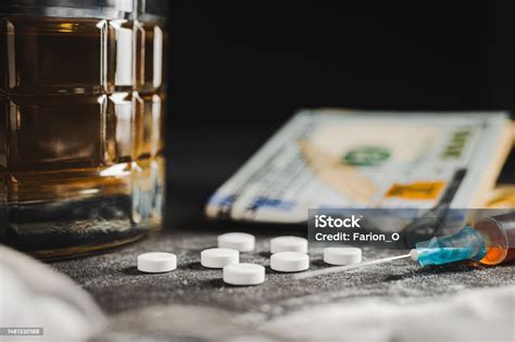 마약 흰색 알약 마약 물질이 들어있는 주사기 흰색 분말 코카인 유리에 담긴 알코올 음료 및 어두운 배경에 미국 달러 통화 중독 학대 및 나쁜 습관의 개념 0명에 대한 스톡