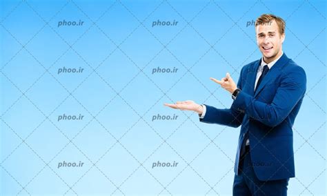 عکس مرد با کت شلوار در حال اشاره به چیزی در پس زمینه آبی عکس با کیفیت و تصاویر استوک حرفه ای