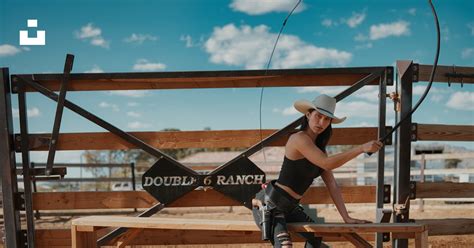 검은 탱크 탑과 파란색 데님 청바지를 입은 여자는 갈색 나무에 앉아 흰색 모자를 쓰고 있다 사진 Unsplash의 무료 더블 6 랜치 이미지