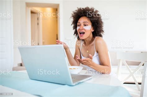 옥수수 조각을 들고 노트북과 테이블에 실내에 앉아 행복 젊은 놀라운 여자의 이미지 노트북 컴퓨터를 보고 화상 통화를 통해 친구들과 이야기 먹기에 대한 스톡 사진 및 기타