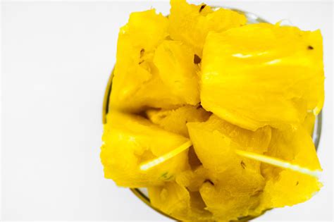 창조적 인 클로즈업 매크로 고립 된 흰색 배경에 잘 익은 파인애플 조각의 상단 보기 건강한 음식 패턴의 유리 그릇에 신선한 육즙이 많은 노란색 과일 조각 텍스트에 대한 복사