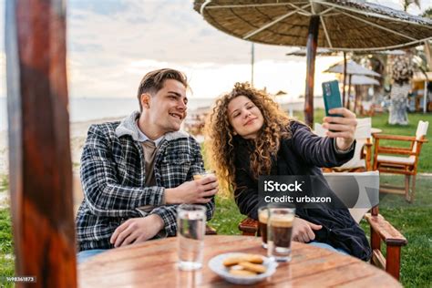 Young Couple Taking Selfies While Drinking Coffee In A Beach Bar In