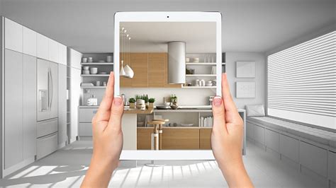 손을 잡고 현대 흰색과 나무 부엌을 보여주는 태블릿 총 빈 프로젝트 배경 증강 현실 개념 가구 및 인테리어 디자인 제품을 시뮬레이션 하는 응용 프로그램 가구에 대한 스톡