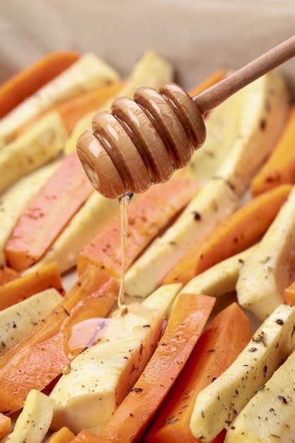 Premium Photo Pouring Honey Onto Slices Of Parsnip And Carrot Closeup
