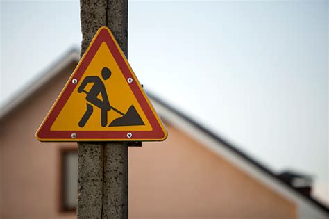 밝은 노란색 삼각형 경고 기호 주의 작업 높은 푸른 하늘 복사 공간 배경 흐리게 집에 콘크리트 기둥에 게시 합니다 수리 및도 건설 개념입니다 거리에 대한 스톡 사진 및 기타