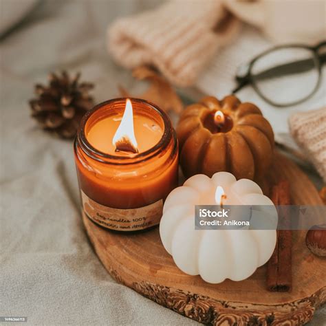 나무 심지가 있는 유리병에 향기로운 양초와 호박의 양초 모양 머그잔에 레몬 차가 있는 가을 구성 아로마테라피 명상 웰빙의 개념