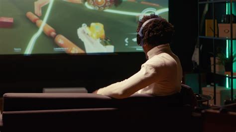 Man Playing Singleplayer Videogames On Ultrawide Smart Tv Putting Headphones On To Feel