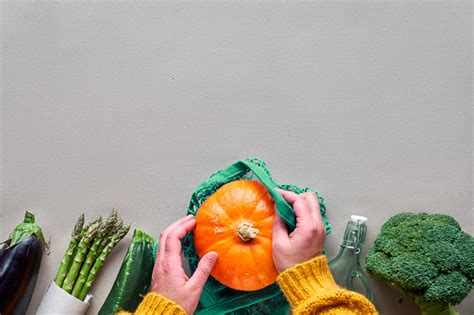 환경 친화적 인 제로 폐기물 플랫 오렌지 호박 브로콜리와 문자열 가방을 들고 손으로 누워 공예 종이 배경 텍스트 공간에 야채와 손으로 평평한 평신도가 됩니다 가지 채소에