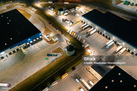 밤에 상품 창고의 조감도 트레일러가 달린 많은 창고와 트럭이 주차장에 있으며 전국에 상품이 추가로 배포되기 위해 적재되기를 기다리고 있습니다 건축물에 대한 스톡 사진 및