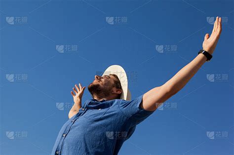 一个伸开双臂站在海滩上的男人