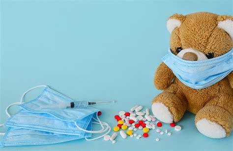 의료 보호 마스크에 장난감 곰 백신 주사기 파란색 배경에 여러 가지 색깔의 알약 보호 코로나 바이러스 예방 감기 질병 감기 및 독감의 개념copy 공간 0명에 대한 스톡