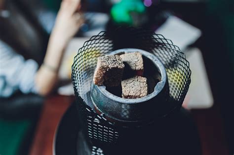 붉은 뜨거운 석탄을 곁들인 시샤 후카 호흡에서 불꽃 코코넛 숯과 시샤 연기가 있는 모던 한 후카 후카와 석탄에서 불꽃 흡연 자연 조명에 대한 전통적인 Hookah 뜨거운