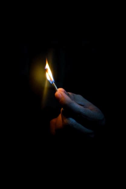 Premium Photo Cropped Hand Holding Illuminated Matchstick In Darkroom