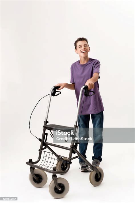 뇌성 마비가 카메라에 미소와 행복 한 십대 장애인 소년의 전체 길이 샷 흰색 배경에 고립 된 그의 워커와 함께 조치를 복용 뇌성 마비에 대한 스톡 사진 및 기타 이미지