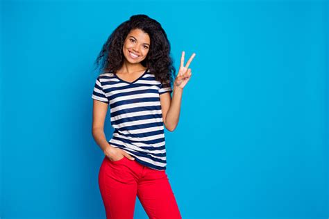 매력적인 달콤한 소녀 아프로 미국 여성의 초상화는 여름 휴가에 재미를 가지고 V징후는 파란색 색상 배경 위에 고립 된 캐주얼 스타일의 의상을 착용 T 셔츠에 대한 스톡 사진