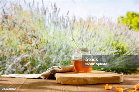 풀과 꽃과 나무의 푸른 초원과 함께 흐릿한 자연과 함께 나무 테이블 위에 꿀 항아리 자연 필드 배경 및 음식과 음료 및 제품에 대한 복사 공간 0명에 대한 스톡 사진 및