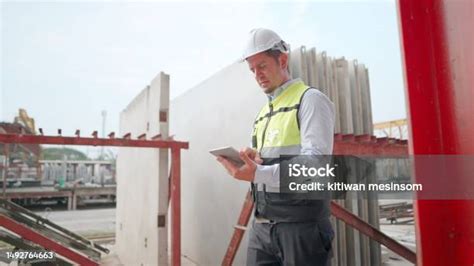 안전 유니폼을 입은 토목 기사 또는 계약자는 건물 또는 주택 프로젝트의 건설 현장에서 프리 캐스트 콘크리트로 건물 주택의 품질 및 생산 공정을 검사합니다 직원 또는 감독이