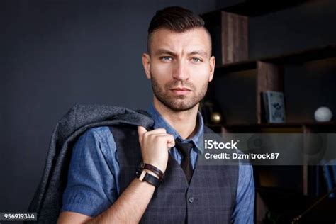 고급 스러운 아파트에 유행 자신감 남자의 클로즈업 초상화 고급 인테리어에 우아한 슈트에 잘생긴 남자입니다 패션 남성 모델 어깨에 자 켓을 보유 하고있다 경외감에 대한 스톡