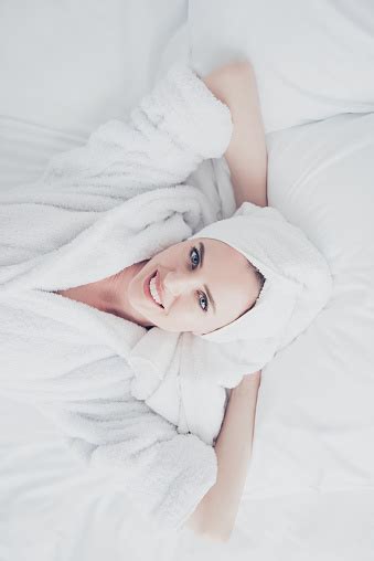 귀여운 사랑 스러운 매력적인 성숙한 여자 흰 시트와 목욕 가운 입고 터 번을 즐기는 베개에 침대에 누워 그녀의 치아와 미소 높은 각도 Veiw 위의 탑 가정 생활에 대한