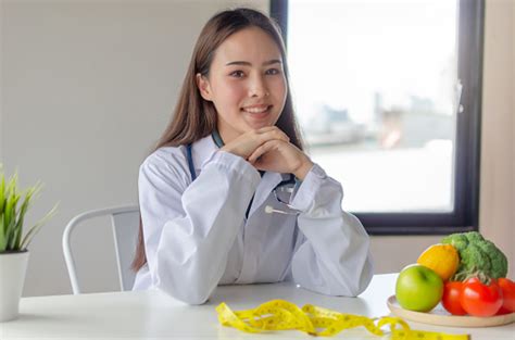 젊은 예쁜 영양사 여성 의사 또는 의료 미소와 실험실 사무실에서 책상에 신선한 야채와 과일 카메라를 보고 영양 라이프 스타일 건강 한 음식과 다이어트 개념 건강관리와 의술에