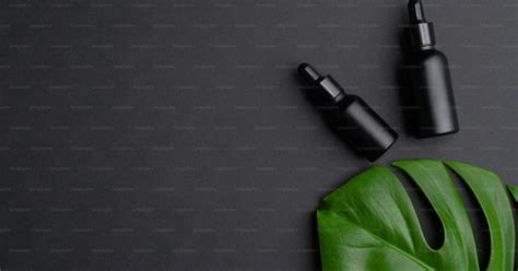 고급 화장품 병과 검은 배경에 열대 몬스 테라 잎 프리미엄 헤어 오일 병 모형 모발 관리 및 치료 개념을 위한 천연 유기농