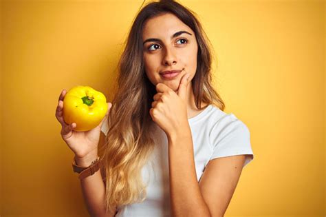 노란색 고립 된 배경 심각한 얼굴에 고추를 들고 젊은 아름다운 여자는 질문에 대해 생각 매우 혼란 스러운 아이디어 개념에 대한 스톡 사진 및 기타 이미지 Istock