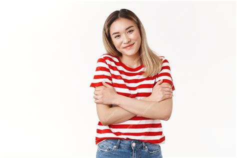 줄무늬 빨간색 티셔츠를 입은 부드러운 귀여운 아시아 여성이 팔짱을 끼고 가슴을 껴안고 저녁에 춥고 쌀쌀한 미소를 지으며 친절하고