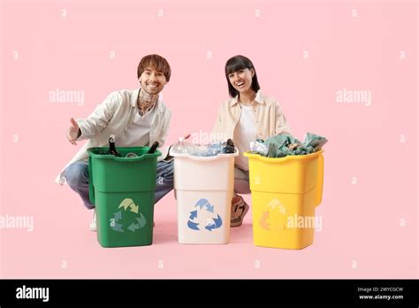 Young Couple With Containers For Garbage Sorting Rubbish On Pink Background Recycling Concept