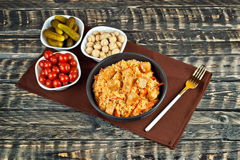 검은 그릇에 고기와 당근을 곁들인 필라프 검은 색 배경에 양념 버섯 토마토와 오이 초라한 테이블에 음식 오래된 나무 판에 그릇 고기에 대한 스톡 사진 및 기타 이미지