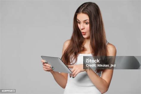 태블릿을 사용 하 여 흰색 셔츠에 행복 한 소녀입니다 태블릿 Pc와 흥분 여자 회색 배경에 고립 경외감에 대한 스톡 사진 및 기타 이미지 Istock