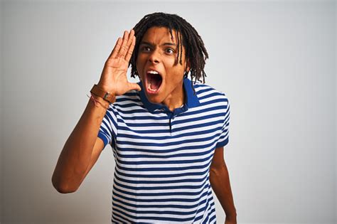 줄무늬 파란색 폴로를 입은 공포를 가진 아프로 남자가 고립된 흰색 배경 위에 서서 입을 다물로 큰 소리로 외치고 비명을 지르고 있습니다 통신 개념입니다 감정에 대한 스톡