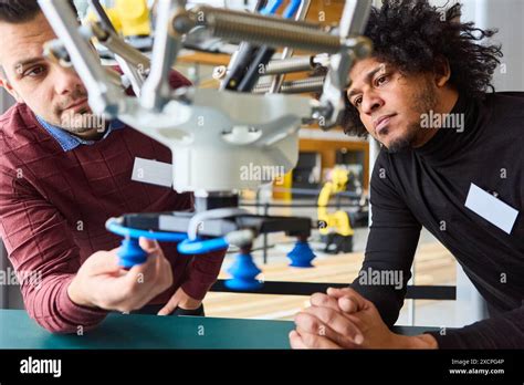 Engineers Closely Inspecting And Programming A Robotic Gripper Arm In A