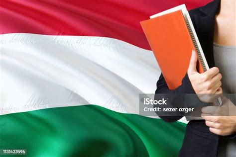 헝가리어 언어 개념 학습 백그라운드에서 헝가리 국기와 함께 서 있는 젊은 여자 책을 들고 교사 오렌지 빈 책 표지 교사 교육