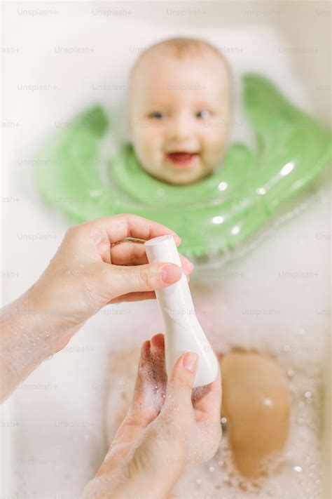 녹색 목 수영 반지로 수영하는 아기 엄마는 튜브에서 샴푸를 짜낸다 사진 Unsplash의 우크라이나 이미지