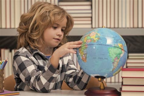 School Pupil Looking At Globe In Library Geography Lesson School