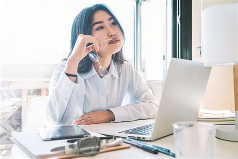 마케팅 전문가 가정에서 일 하는 동안 새 제품 프로 모션에 대 한 새로운 아이디어에 생각 합니다 아시아 학생 여자는 그것에 노트북 테이블에 앉아있는 동안 미래의 직업에 대