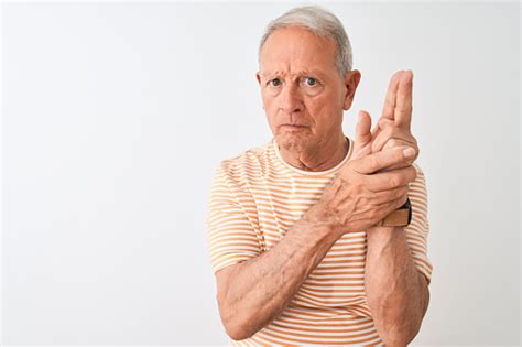 고립 된 흰색 배경 위에 서있는 줄무늬 티셔츠를 입은 선임 회색 머리 남자손 제스처로 상징적 인 총을 들고 살인 사격 무기 화가