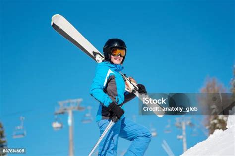 쾌활 한 여성 스키의 미소는 카메라에 그녀의 스키를 들고는 맑은 겨울 날 Copyspace 스키 리프트에 산에 스키장에서 스키를 즐기는 푸른 하늘 배경에서 근접 촬영 겨울에
